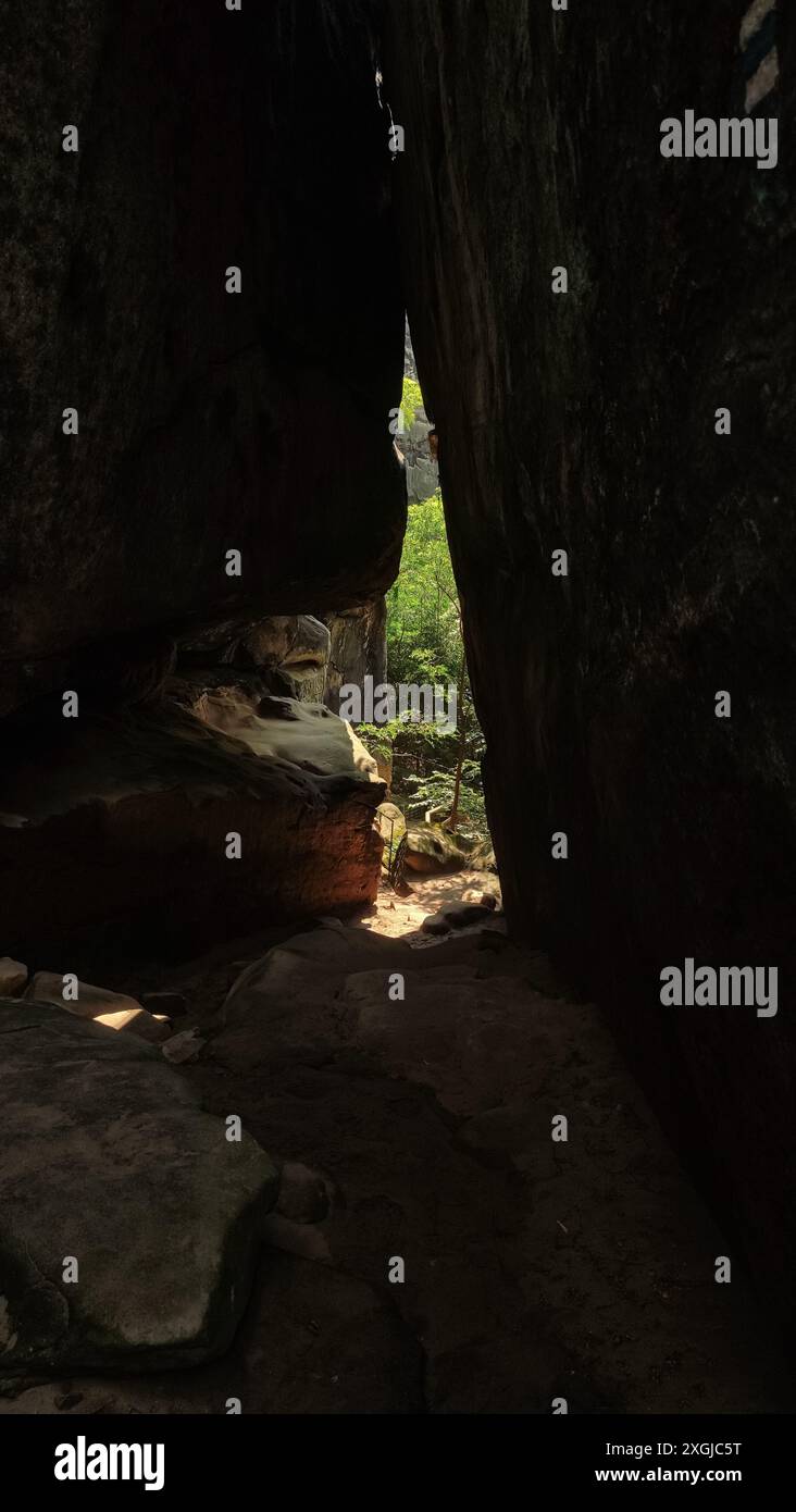 Sunlight streams through a narrow opening in a rocky formation ...