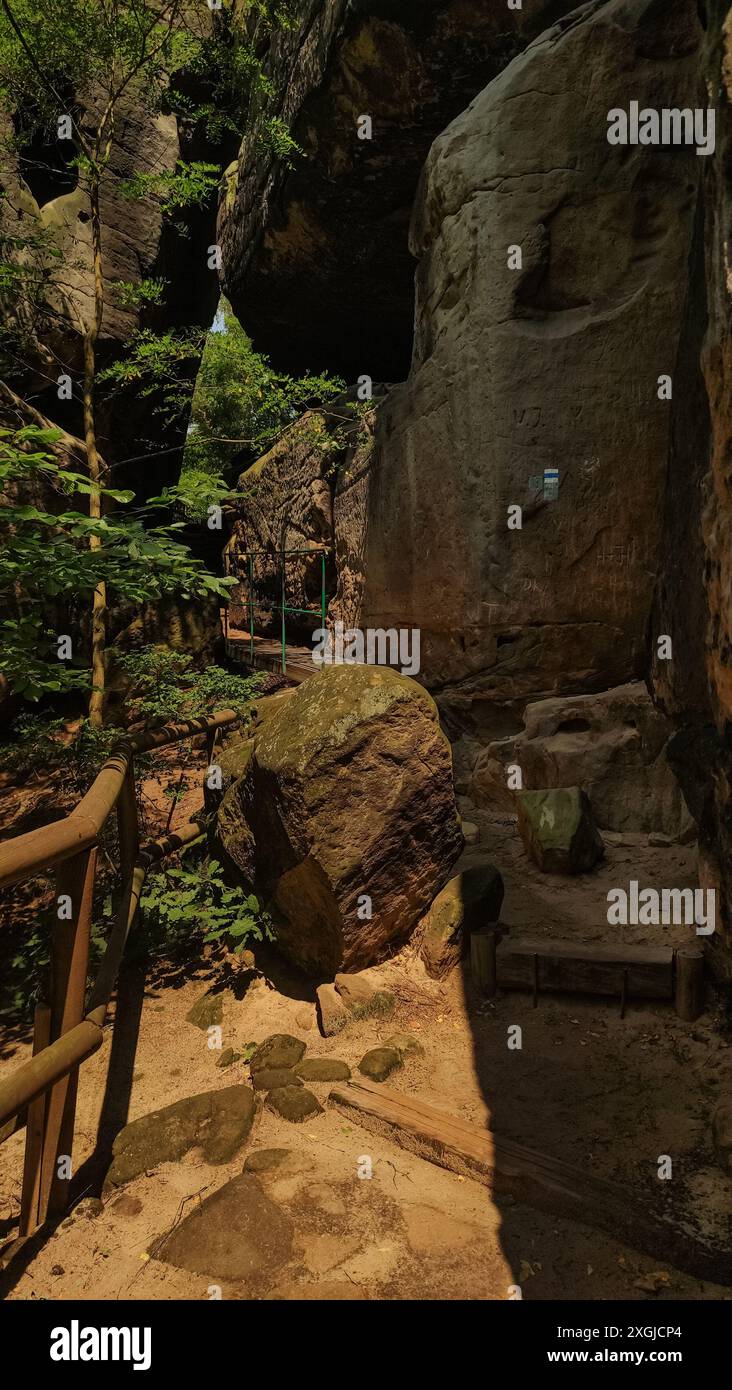 A wooden railing leads through a narrow passage between towering ...