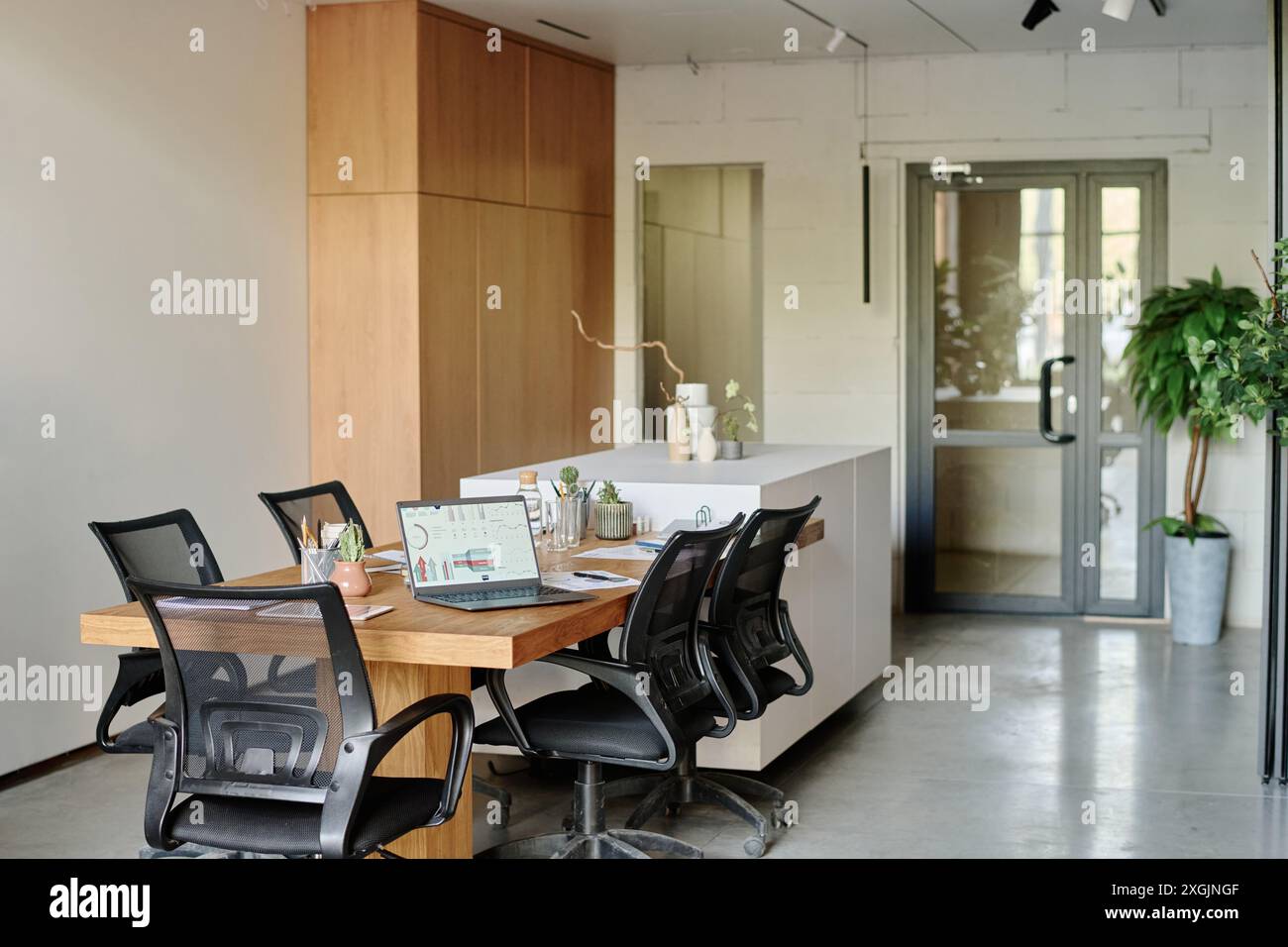 Spacious and light office equipped with wooden table and black chairs ...