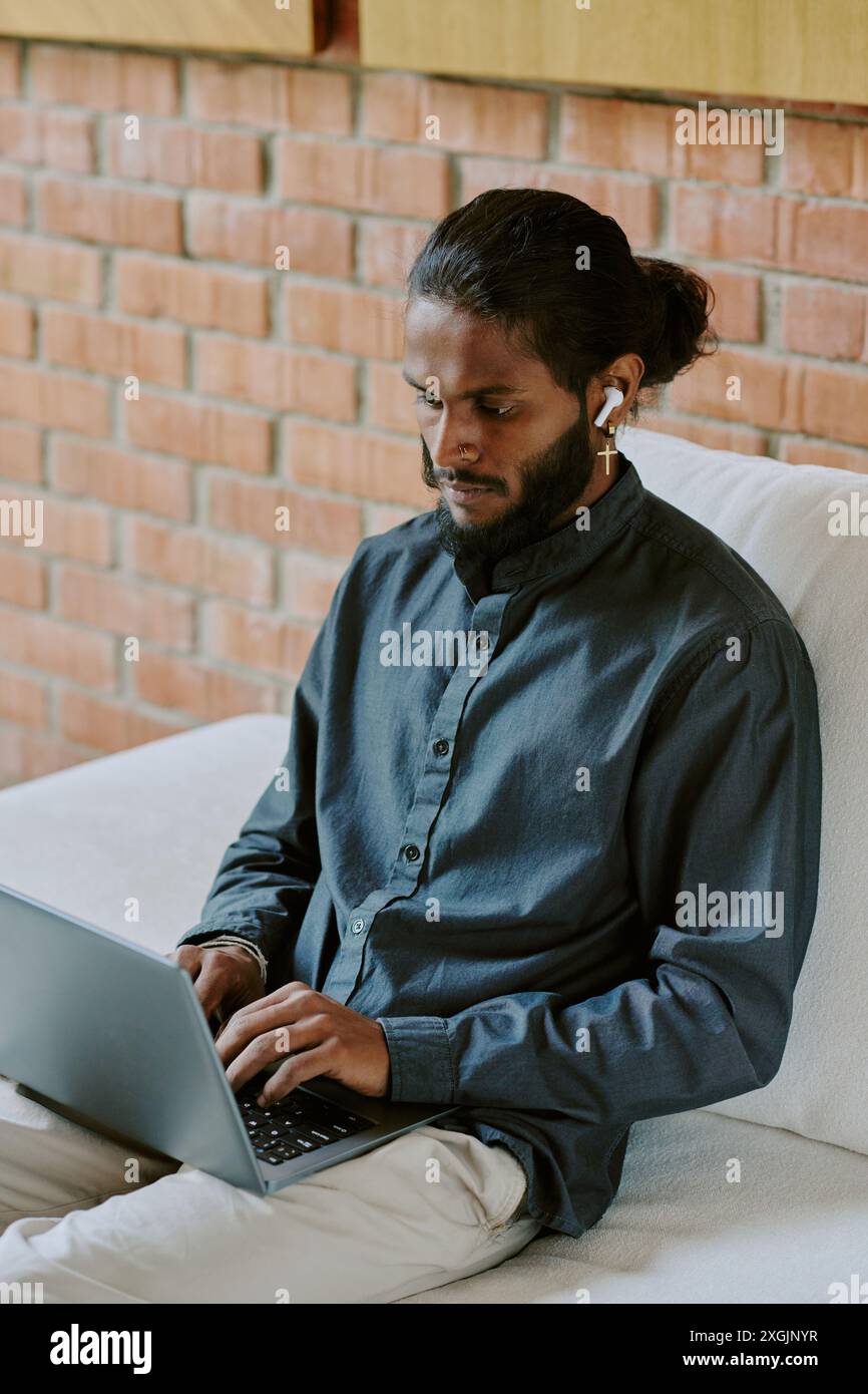 Young Indian influencer sitting on white sofa in office lobby while ...