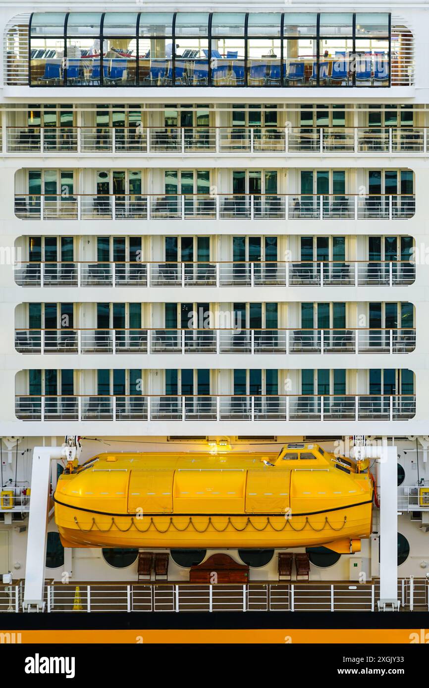 Side view of yellow lifeboat and balconies on a large high cruise ship ...