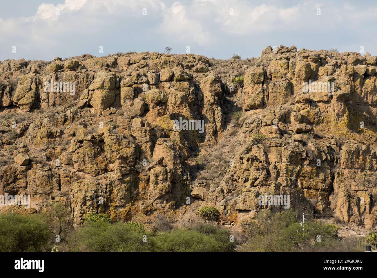 Stunning rocky cliff formation against a background of clouds and lush ...