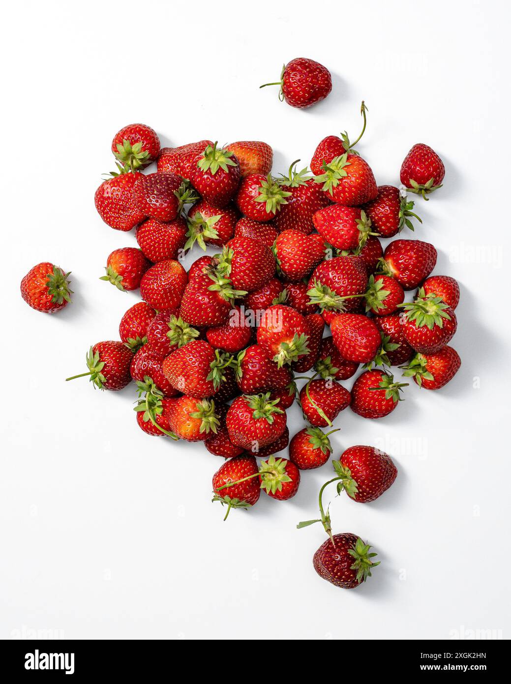 "Top view of a pile of fresh strawberries scattered on a clean white ...
