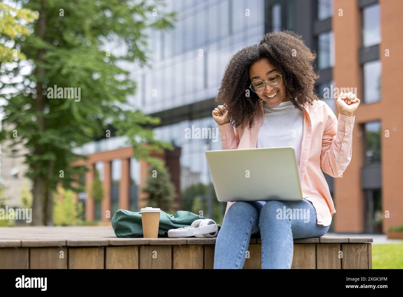 Excited woman enjoying success using laptop in outdoor office setting ...