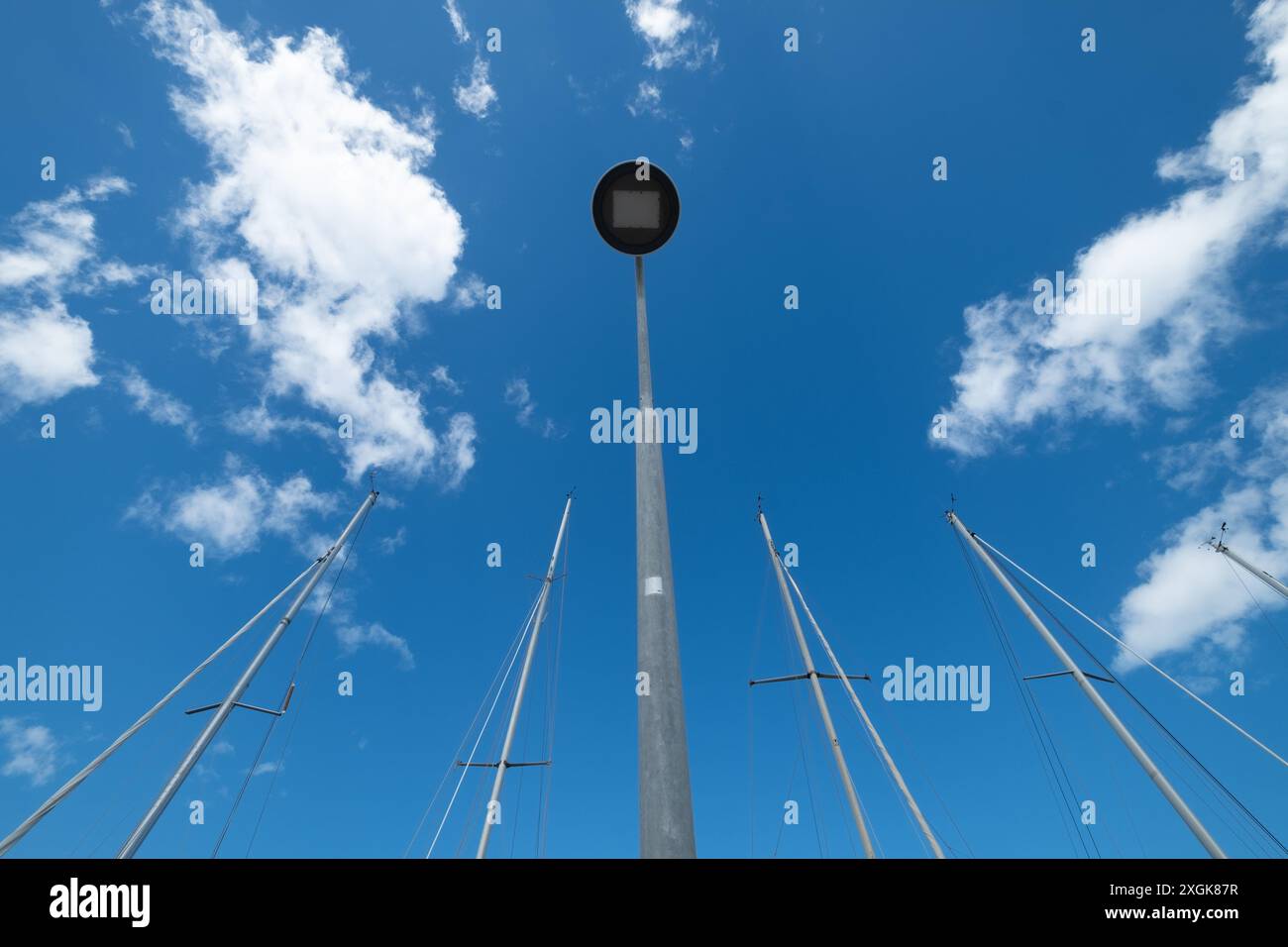 A pole with a light on top stands in front of a blue sky. The pole is ...