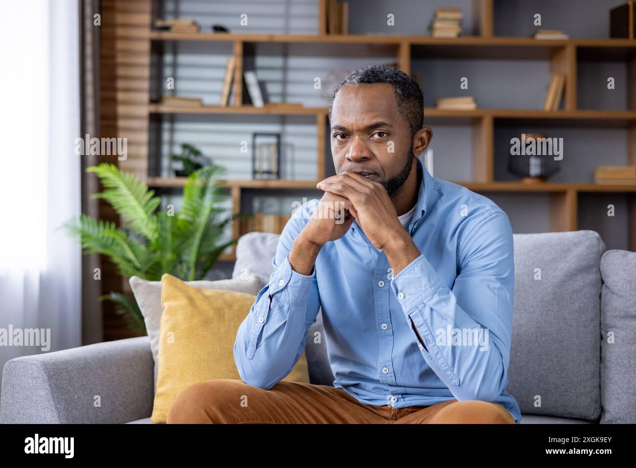 Thoughtful man sitting on couch in modern living room interior with ...