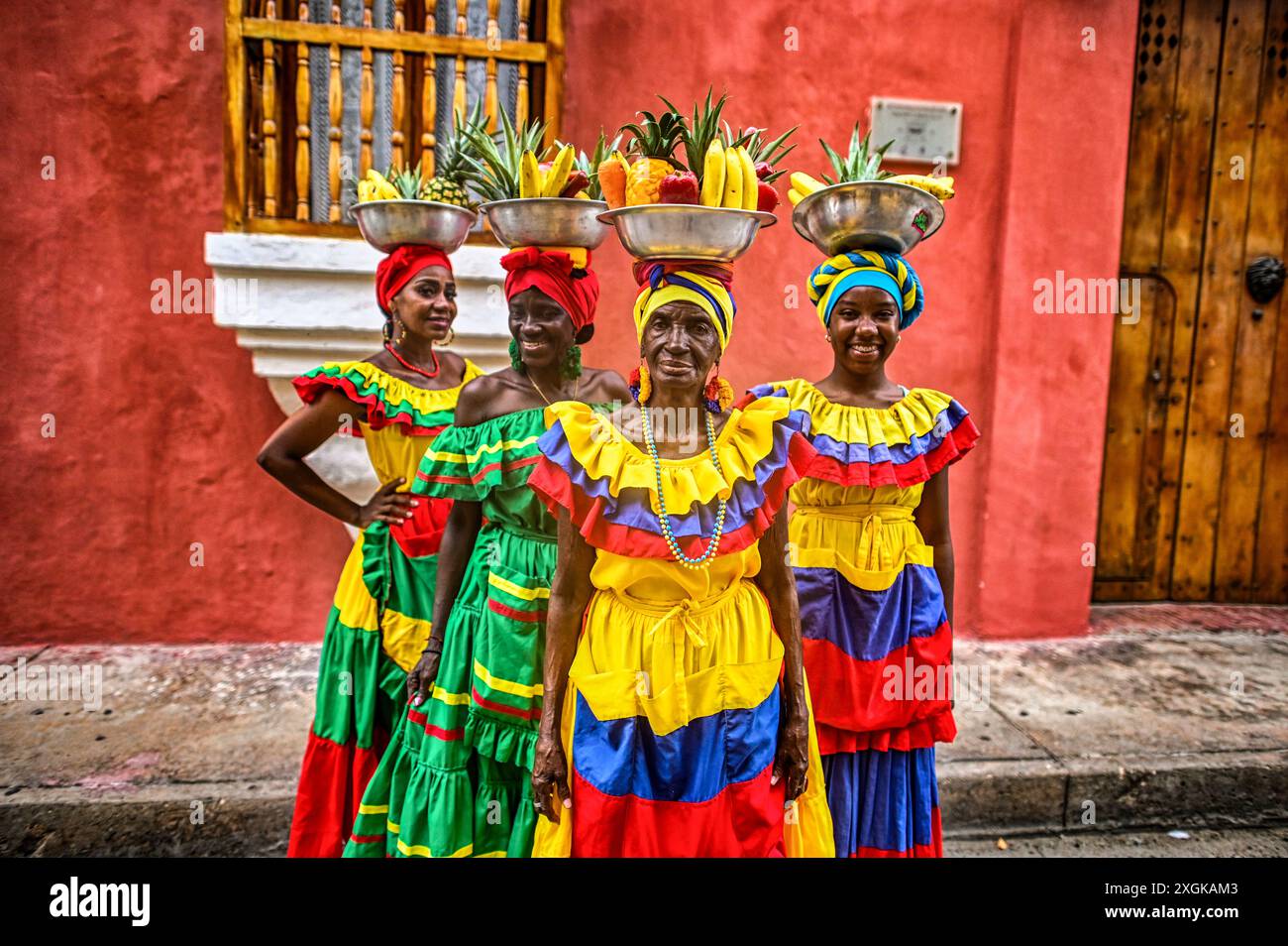 The Palenqueras of Cartagena, dressed in vibrant, colorful outfits with ...
