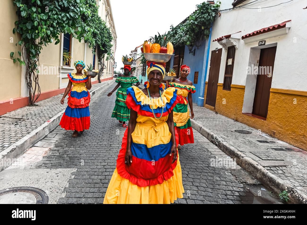 The Palenqueras of Cartagena, dressed in vibrant, colorful outfits with ...
