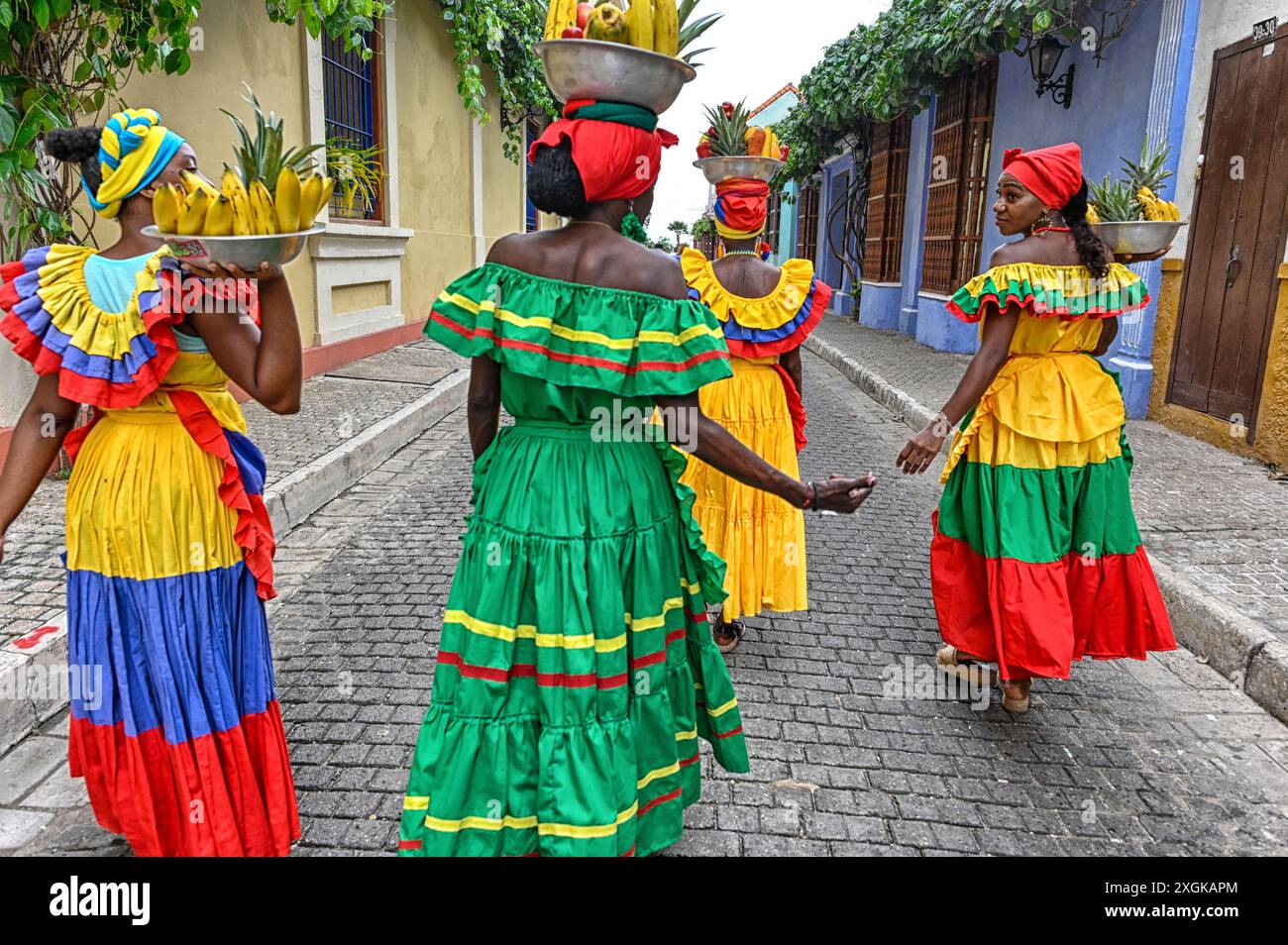 The Palenqueras of Cartagena, dressed in vibrant, colorful outfits with ...