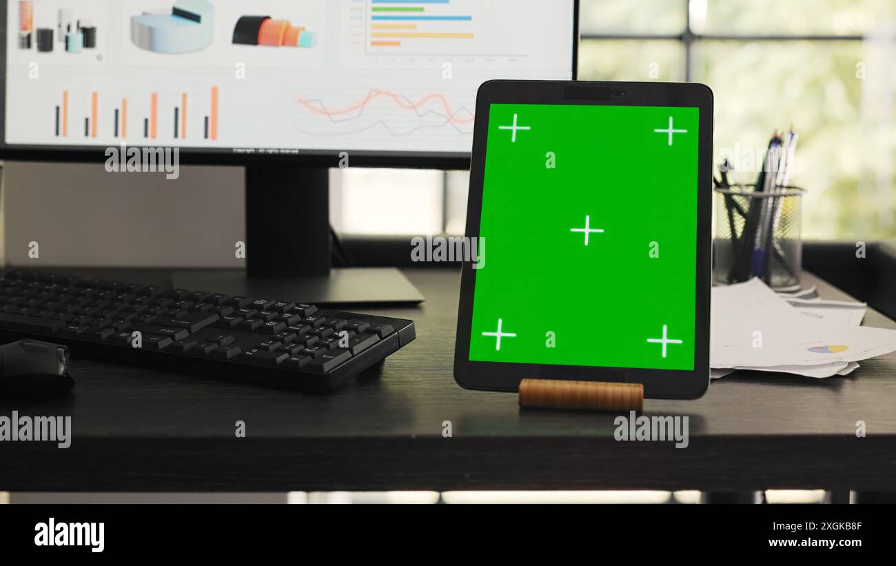 Desk with greenscreen on modern tablet in business coworking space ...