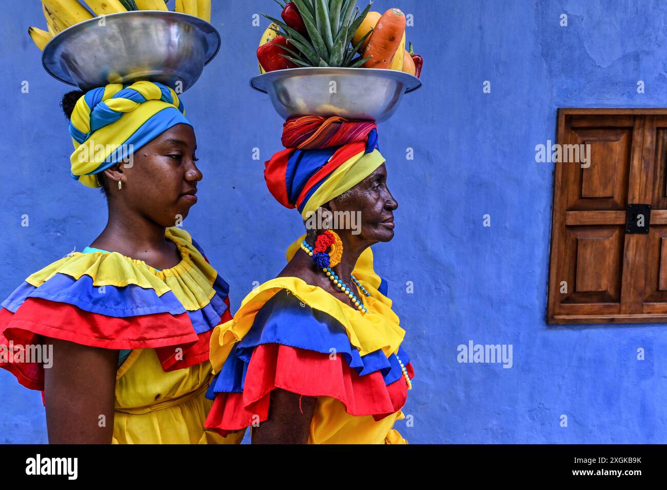 The Palenqueras of Cartagena, dressed in vibrant, colorful outfits with ...