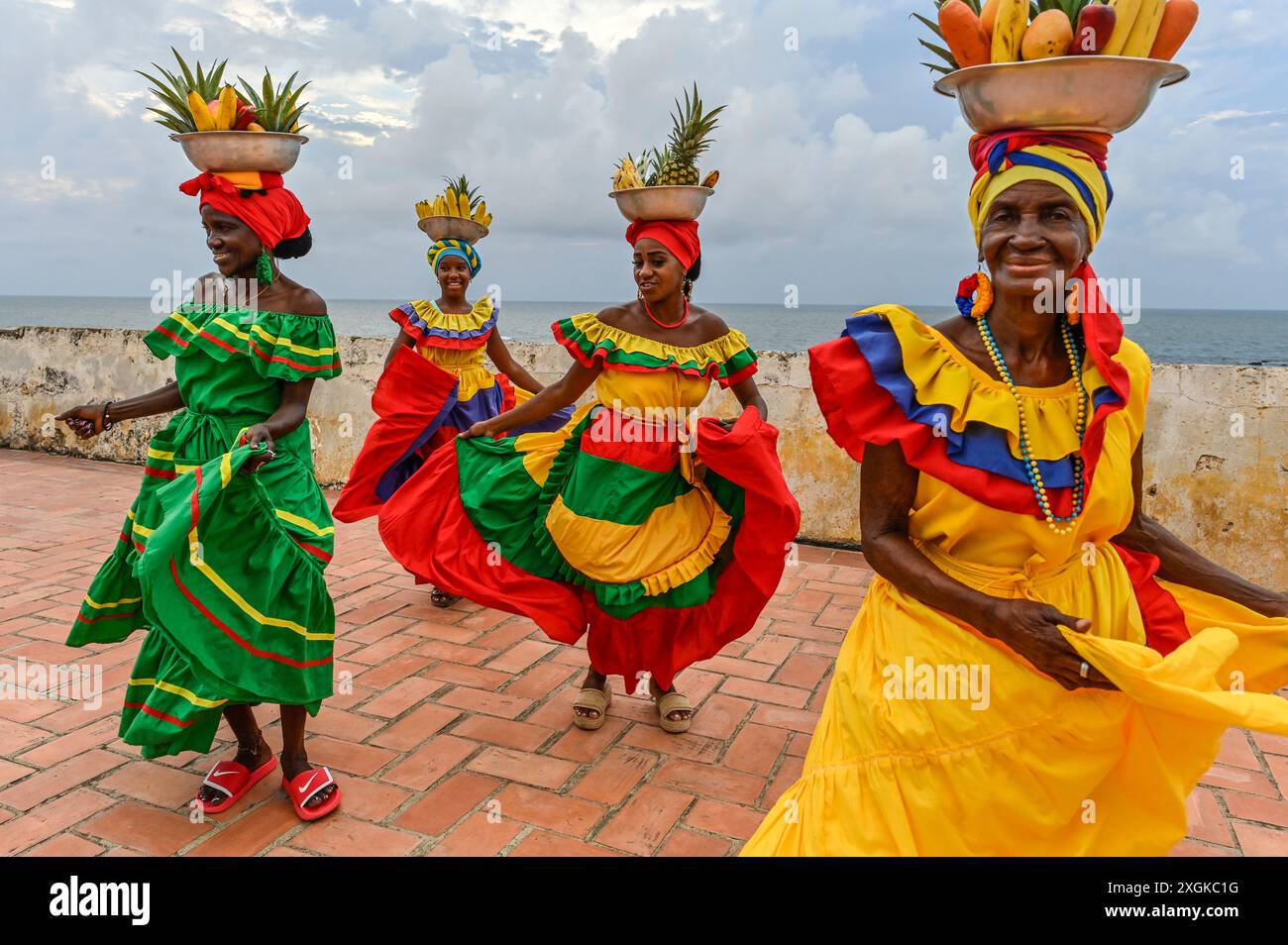The Palenqueras of Cartagena, dressed in vibrant, colorful outfits with ...