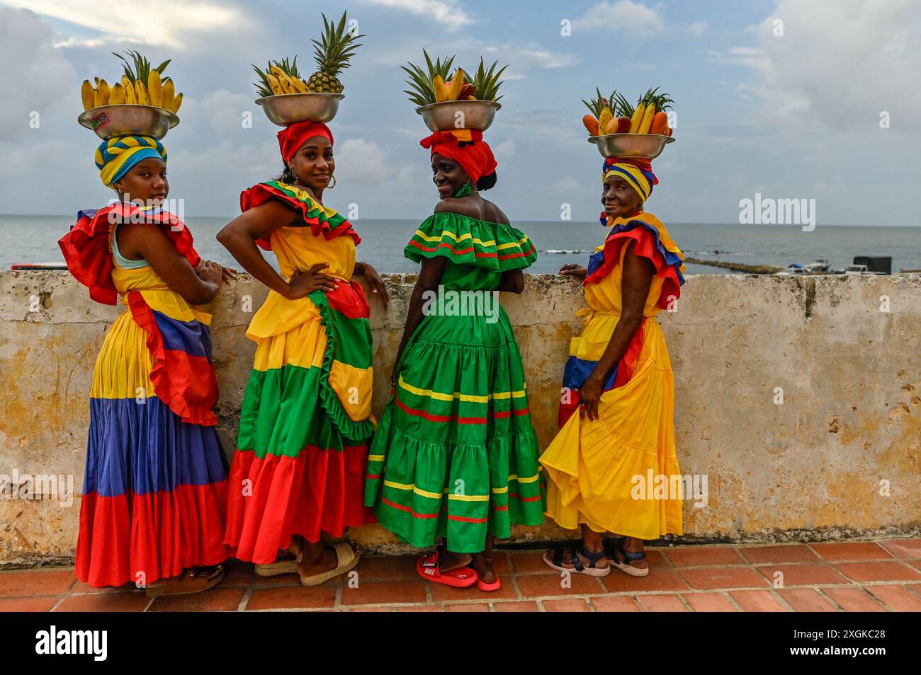The Palenqueras of Cartagena, dressed in vibrant, colorful outfits with ...