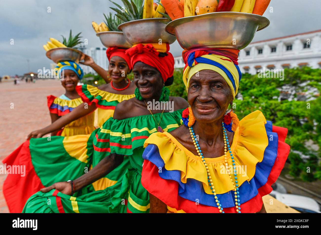 The Palenqueras of Cartagena, dressed in vibrant, colorful outfits with ...