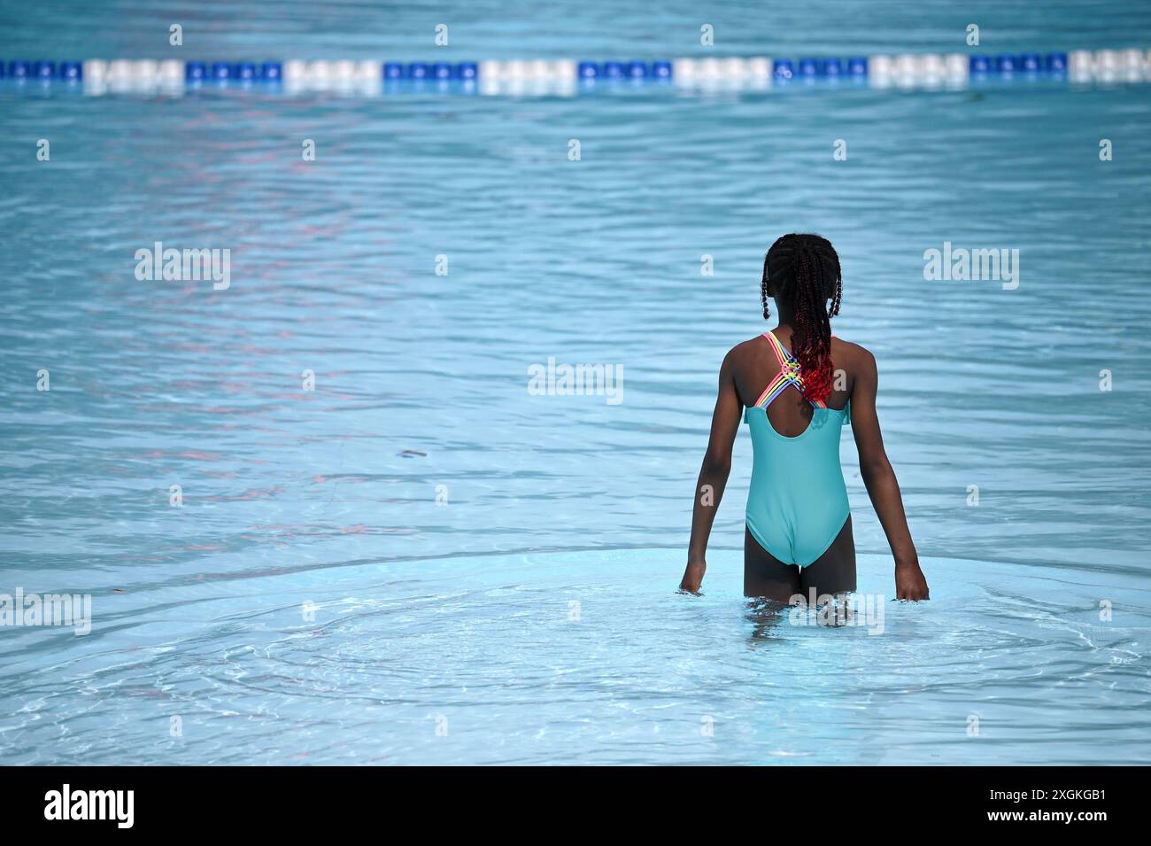 New York, USA. 09th July, 2024. A young bather wades into the shallow ...