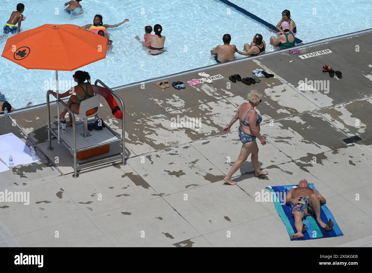 New York, USA. 09th July, 2024. People walk past a man sunbathing at ...