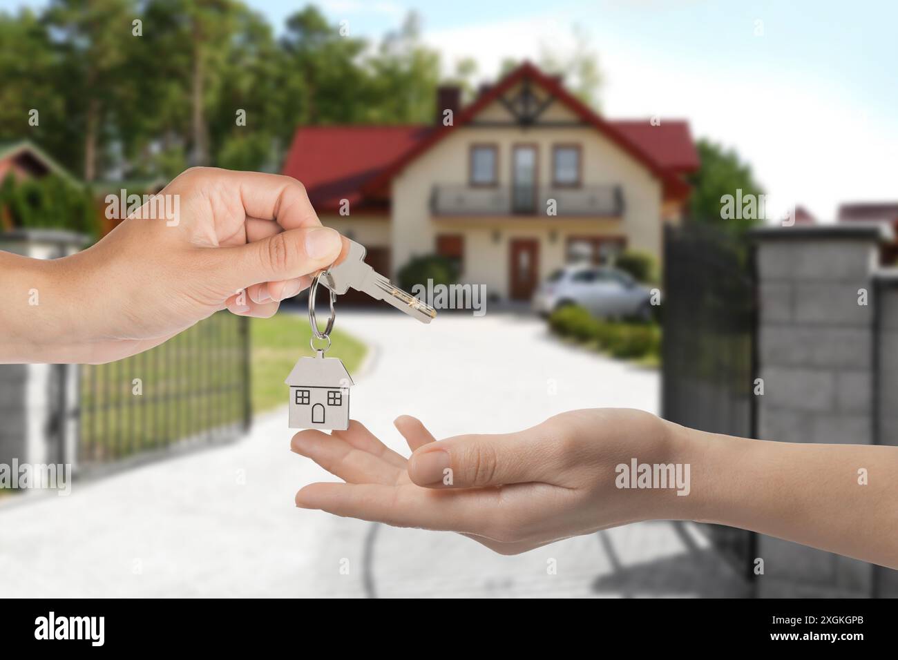 Real estate agent giving house key to new owner against beautiful ...