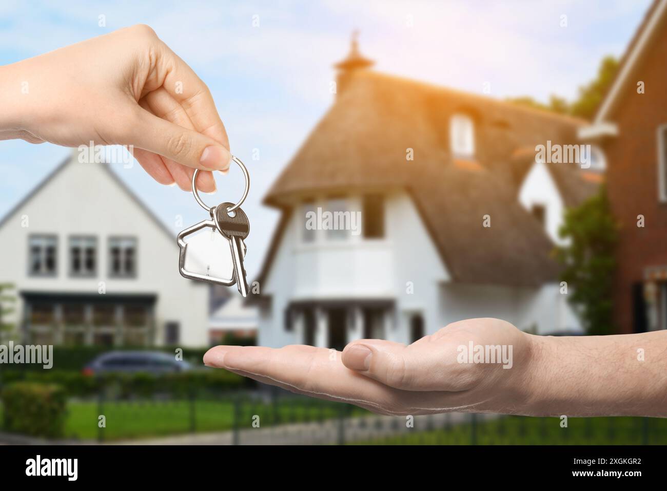 Real estate agent giving house key to new owner against beautiful ...