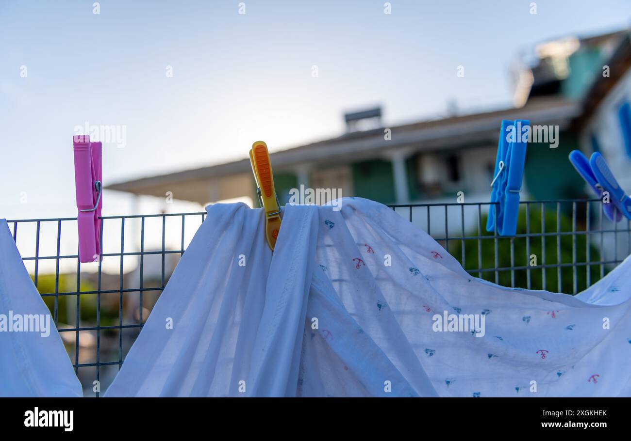 Laundry clothes drying outside on a wired fence held by colourful ...