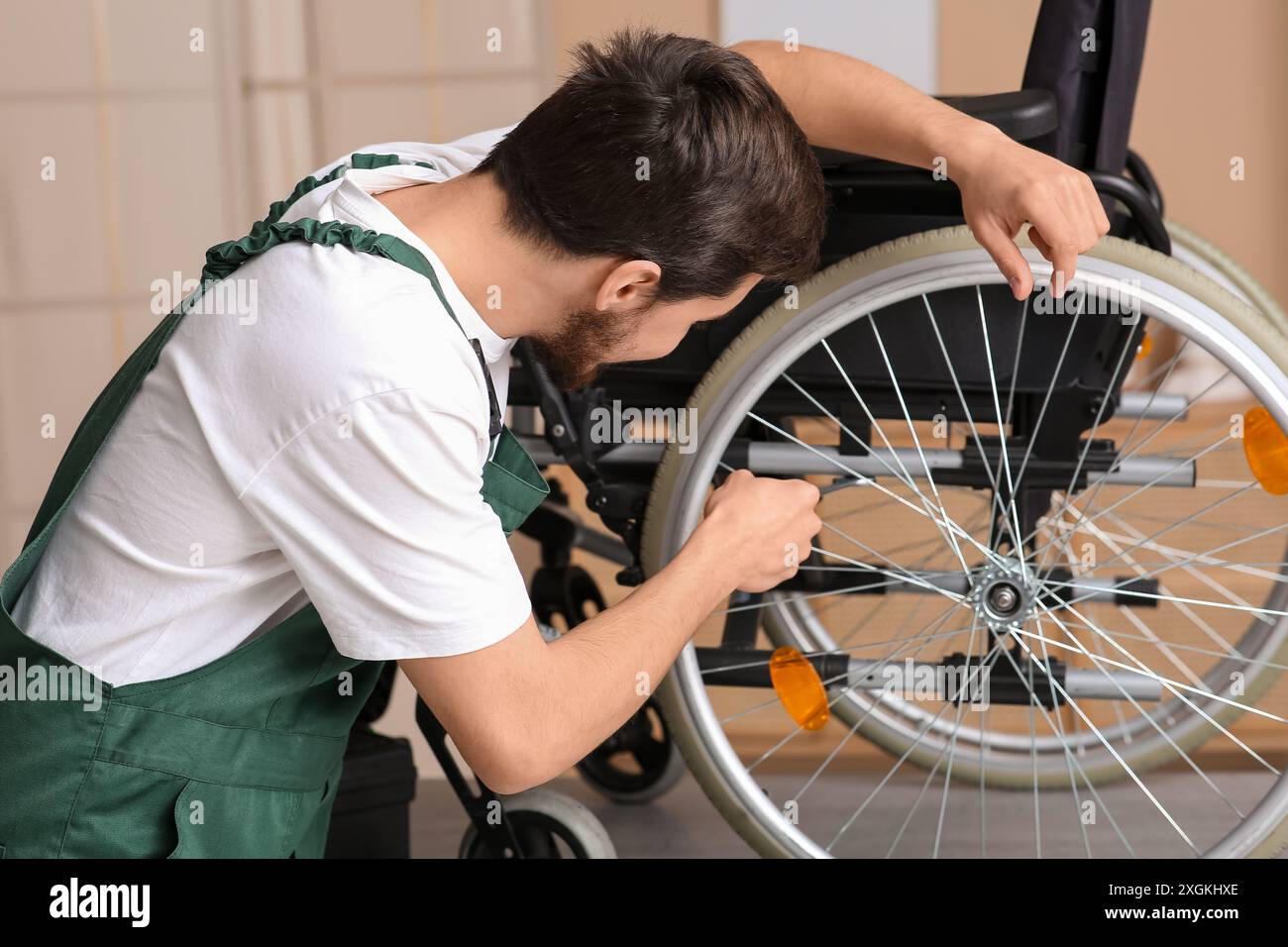 Male worker with wrench repairing wheelchair in room Stock Photo - Alamy