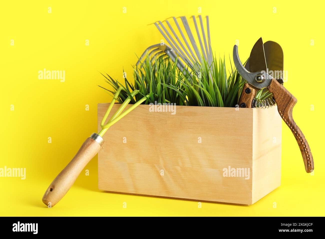 Crate with gardening tools and houseplants on yellow background Stock ...