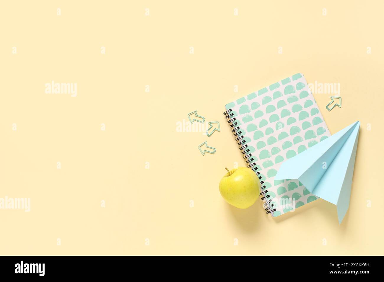 Tasty apple, paper airplane and different school stationery on beige ...