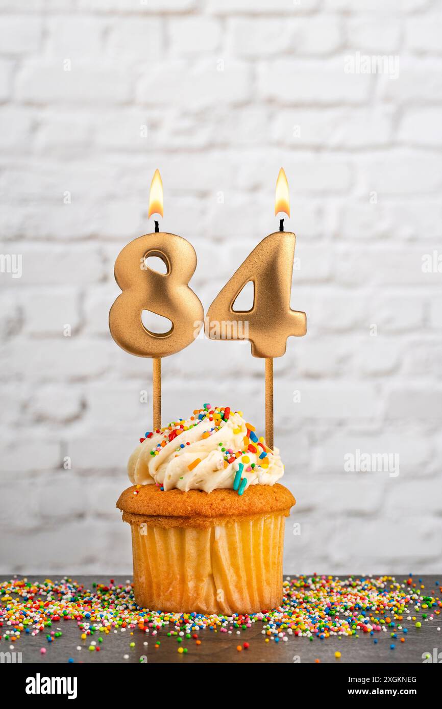 Cupcake with number 84 birthday candle - White block wall background ...