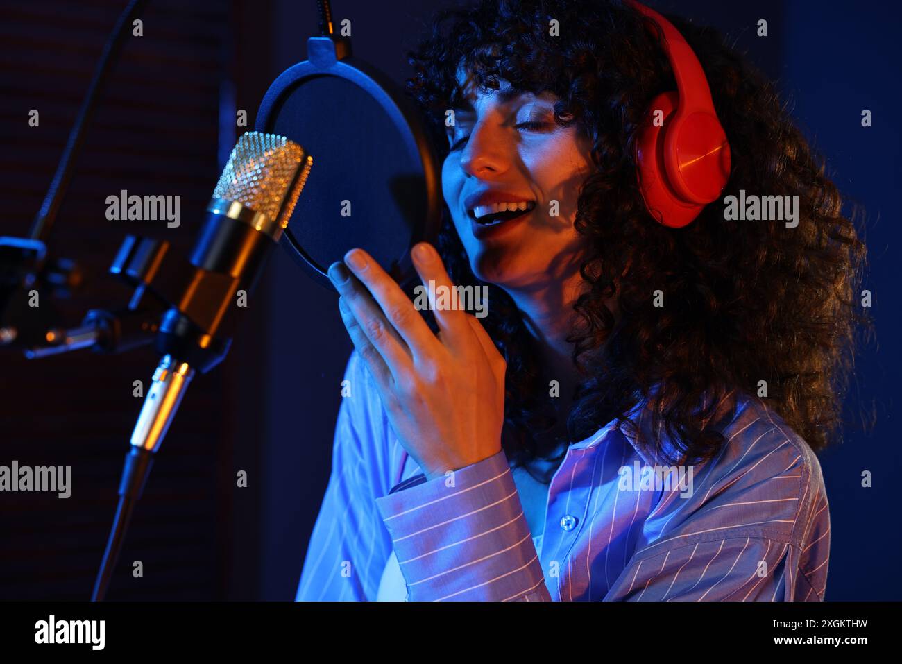 Vocalist singing into microphone in professional record studio with ...