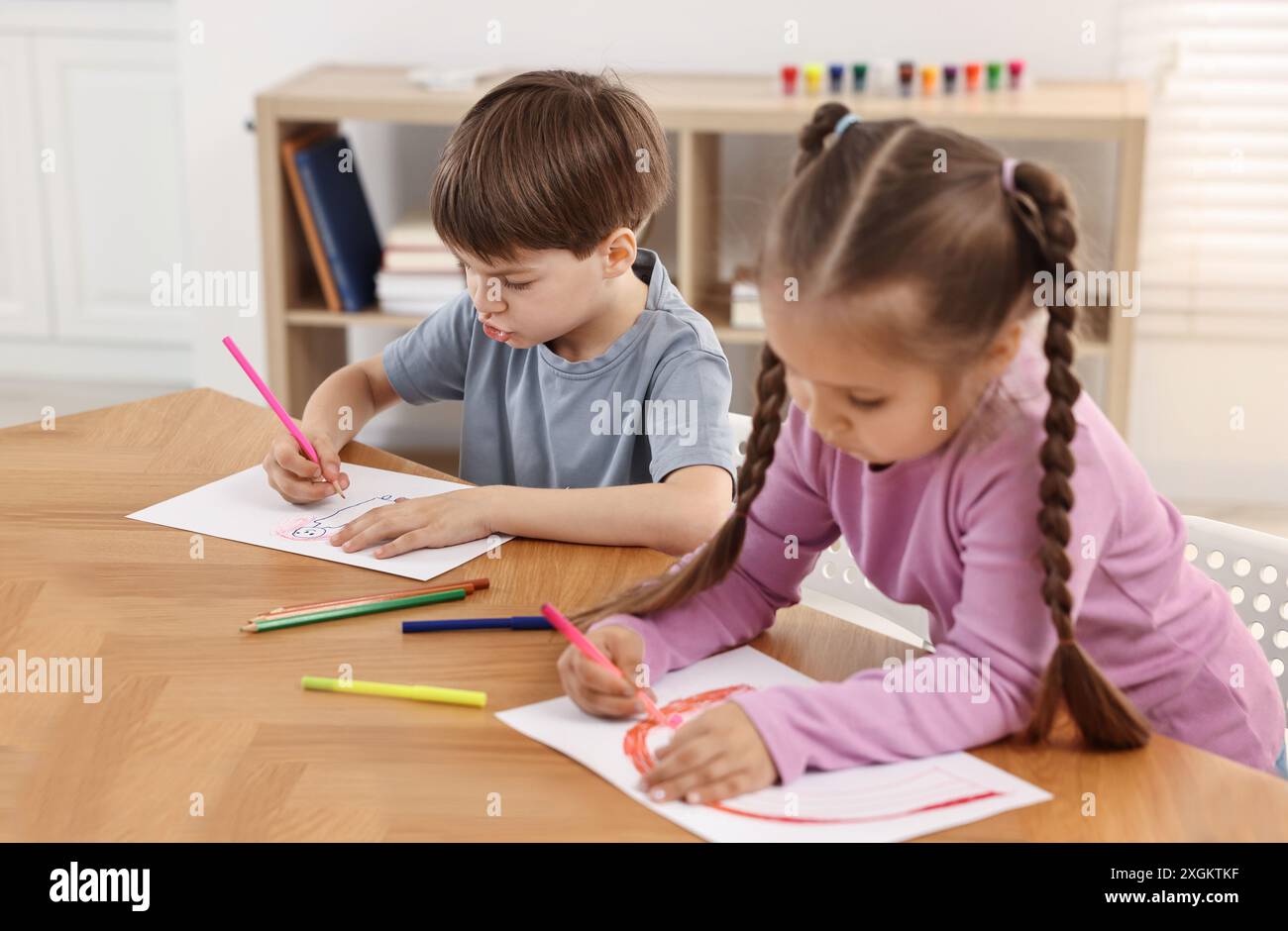 Cute little children drawing at wooden table indoors Stock Photo - Alamy