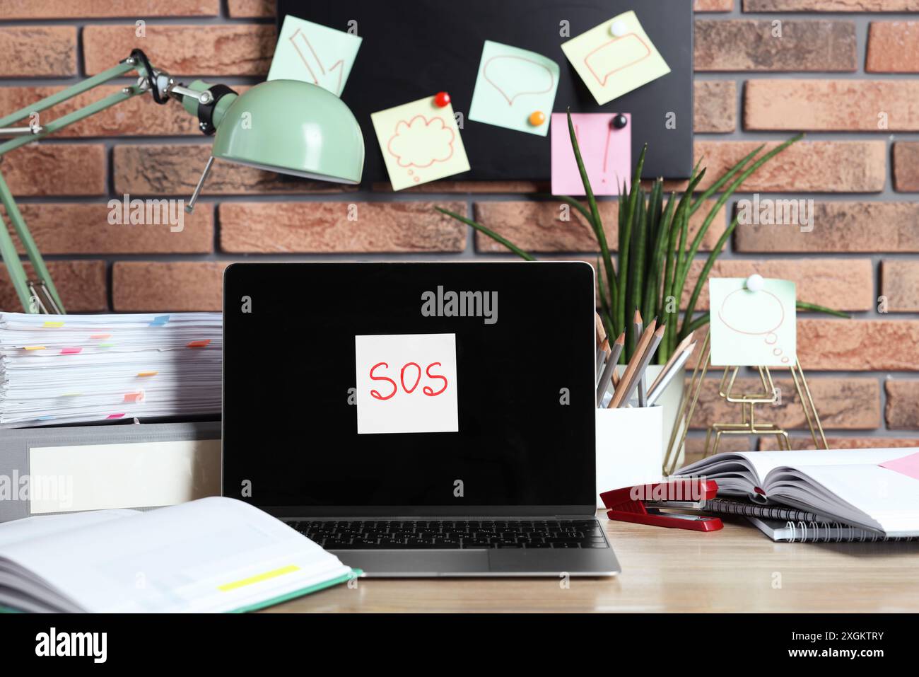 Sticky note with word SOS, laptop and stationery on wooden table at ...