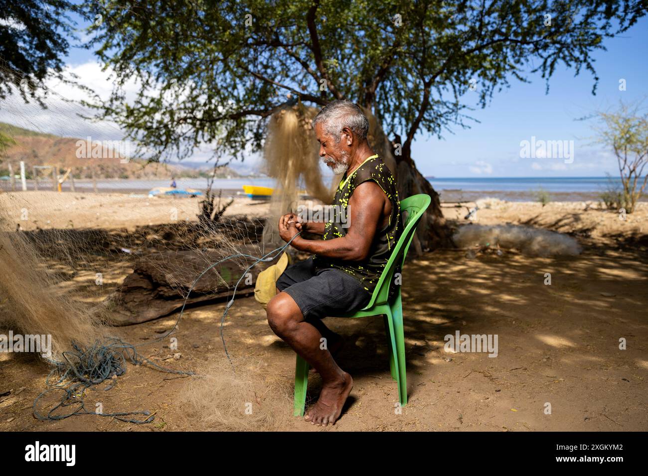 Fisherman mending a fish net on the beach, Dili, Timor-Leste Stock ...