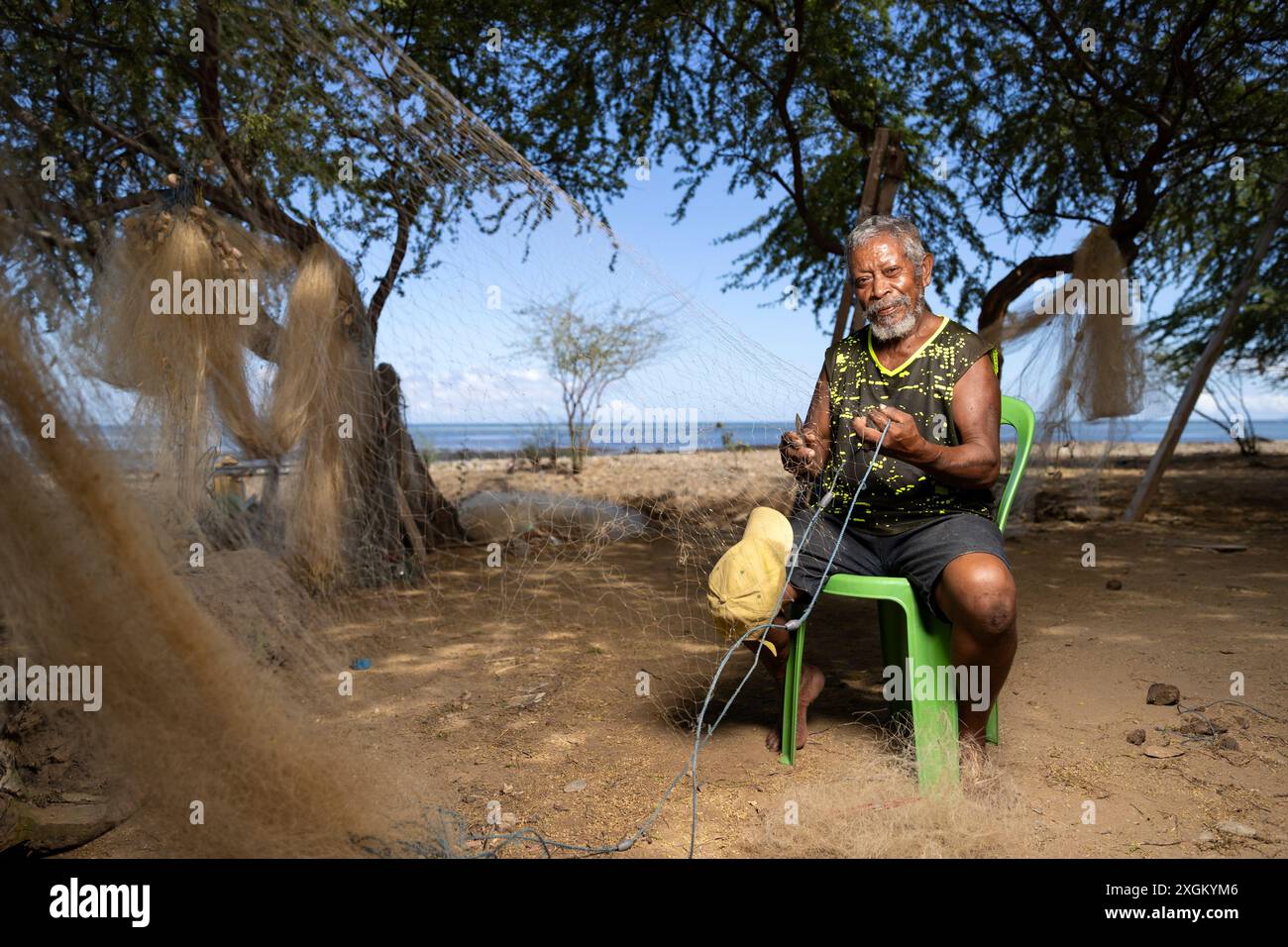 Fisherman mending a fish net on the beach, Dili, Timor-Leste Stock ...