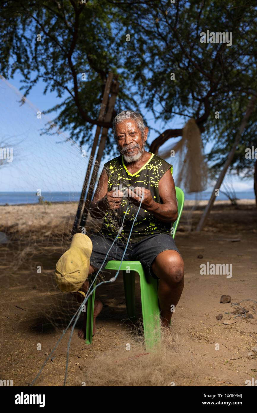 Fisherman mending a fish net on the beach, Dili, Timor-Leste Stock ...