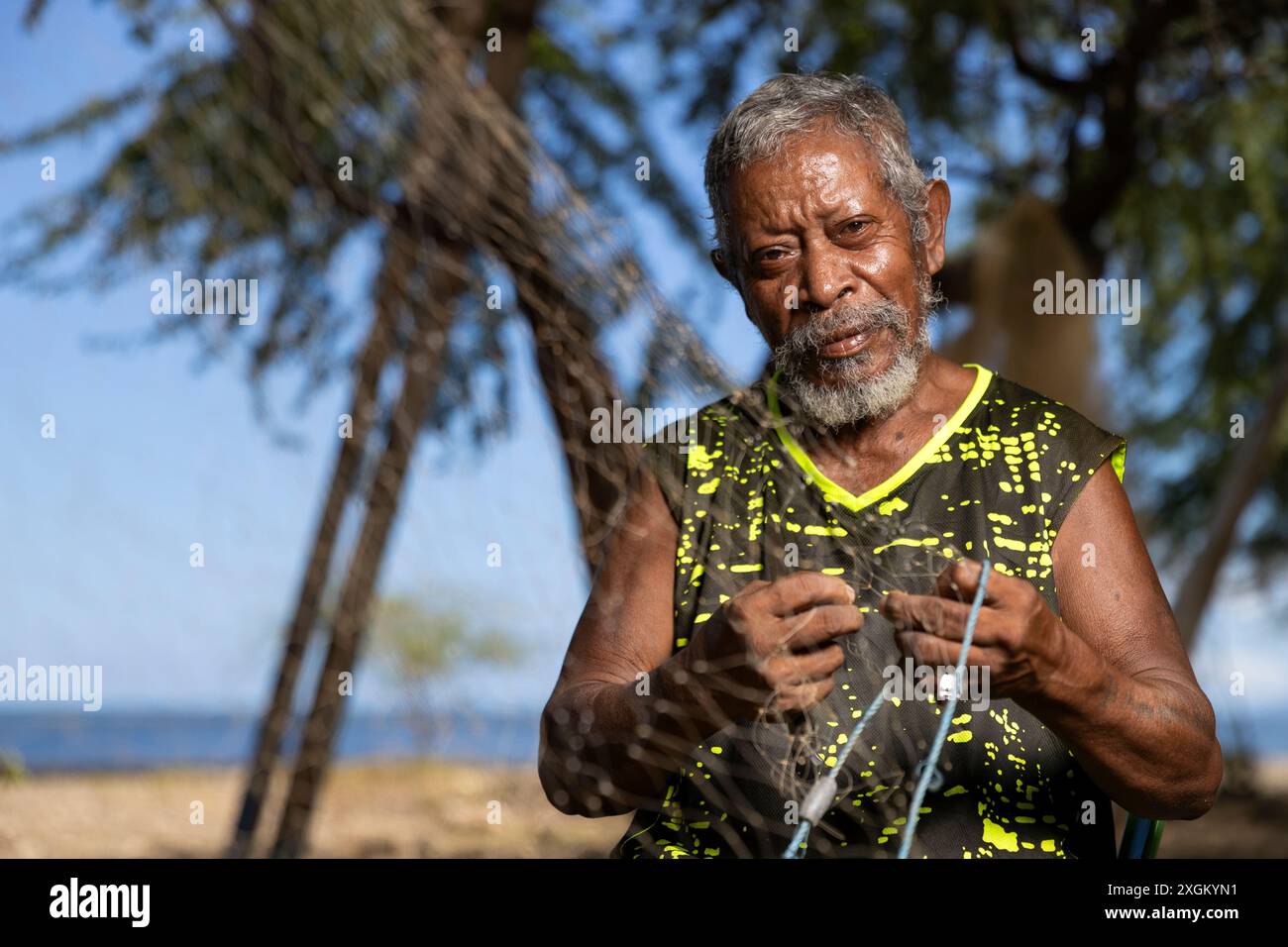 Fisherman mending a fish net on the beach, Dili, Timor-Leste Stock ...