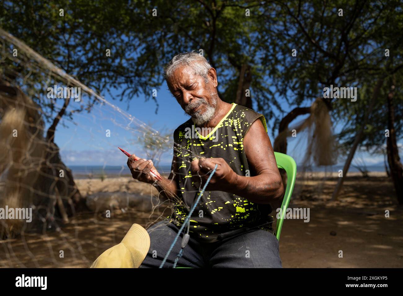 Fisherman mending a fish net on the beach, Dili, Timor-Leste Stock ...