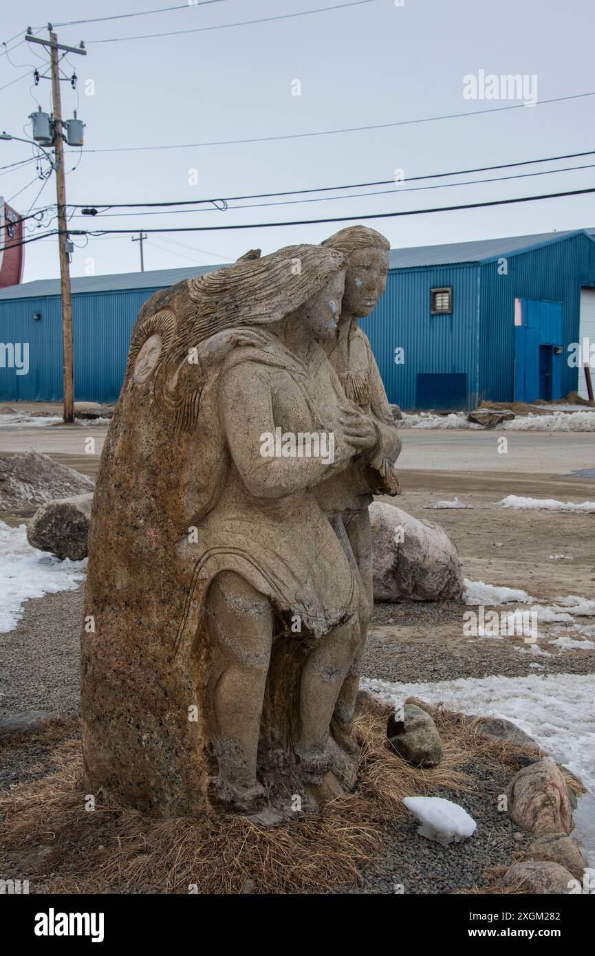 Stone carving of a couple standing by a rock at Inuit sculpture park by ...