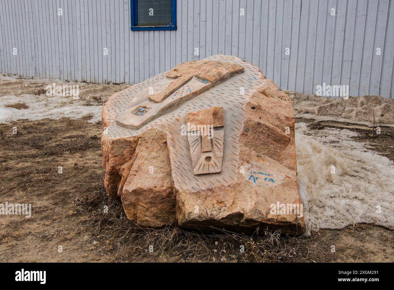 Stone carvings of masked faces on a rock at Inuit sculpture park by the ...