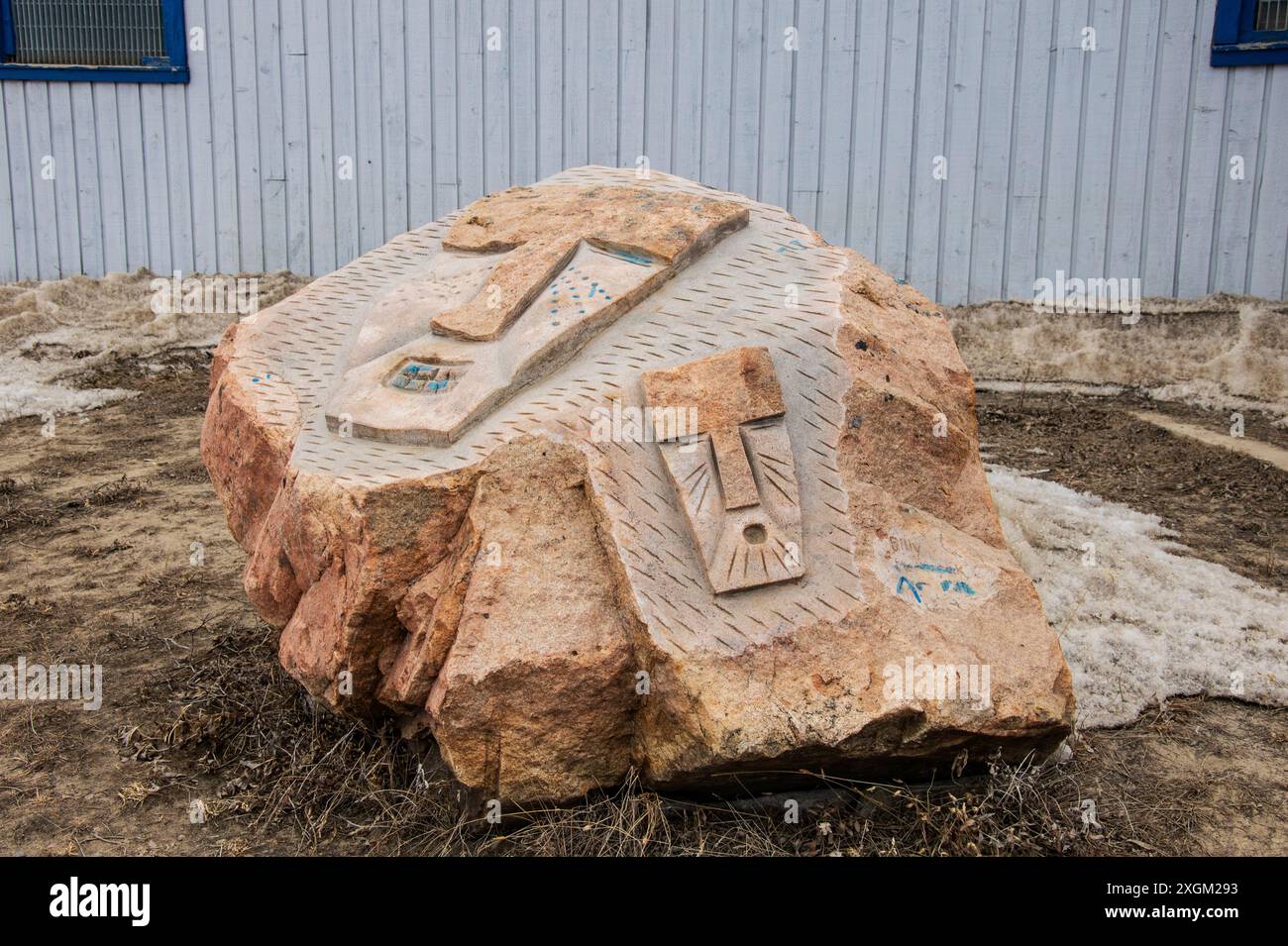 Stone carvings of masked faces on a rock at Inuit sculpture park by the ...