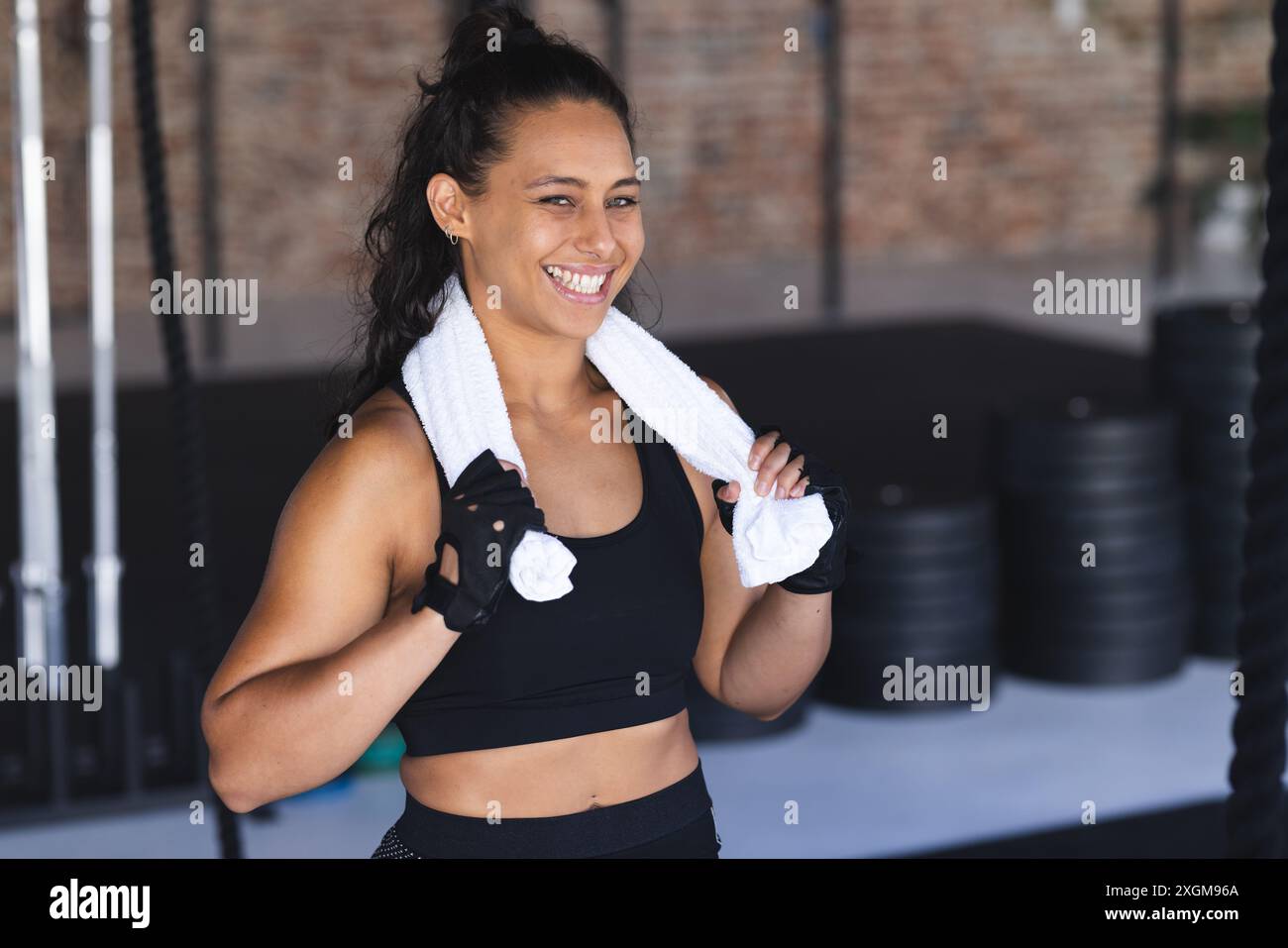 A strong and fit young biracial woman smiles after a workout at the gym ...