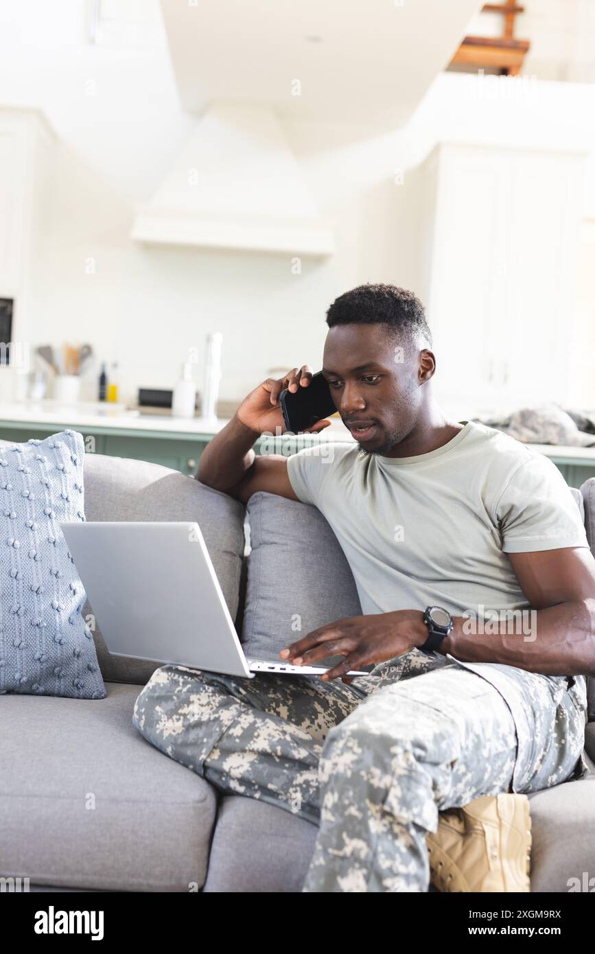 Focused african american male soldier at home using laptop and talking ...