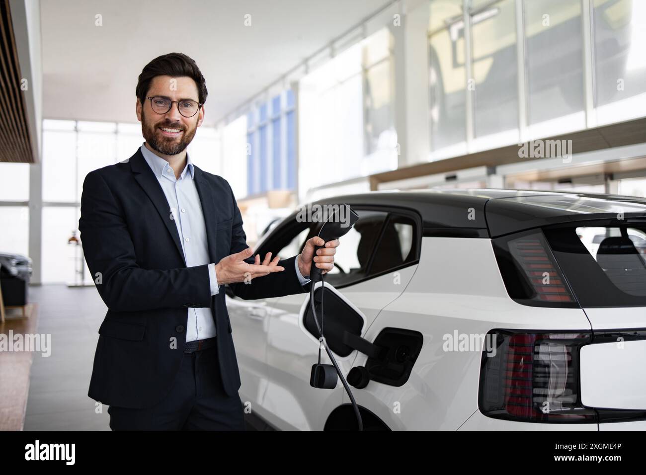 Salesman presenting electric car at vehicle dealership Stock Photo - Alamy