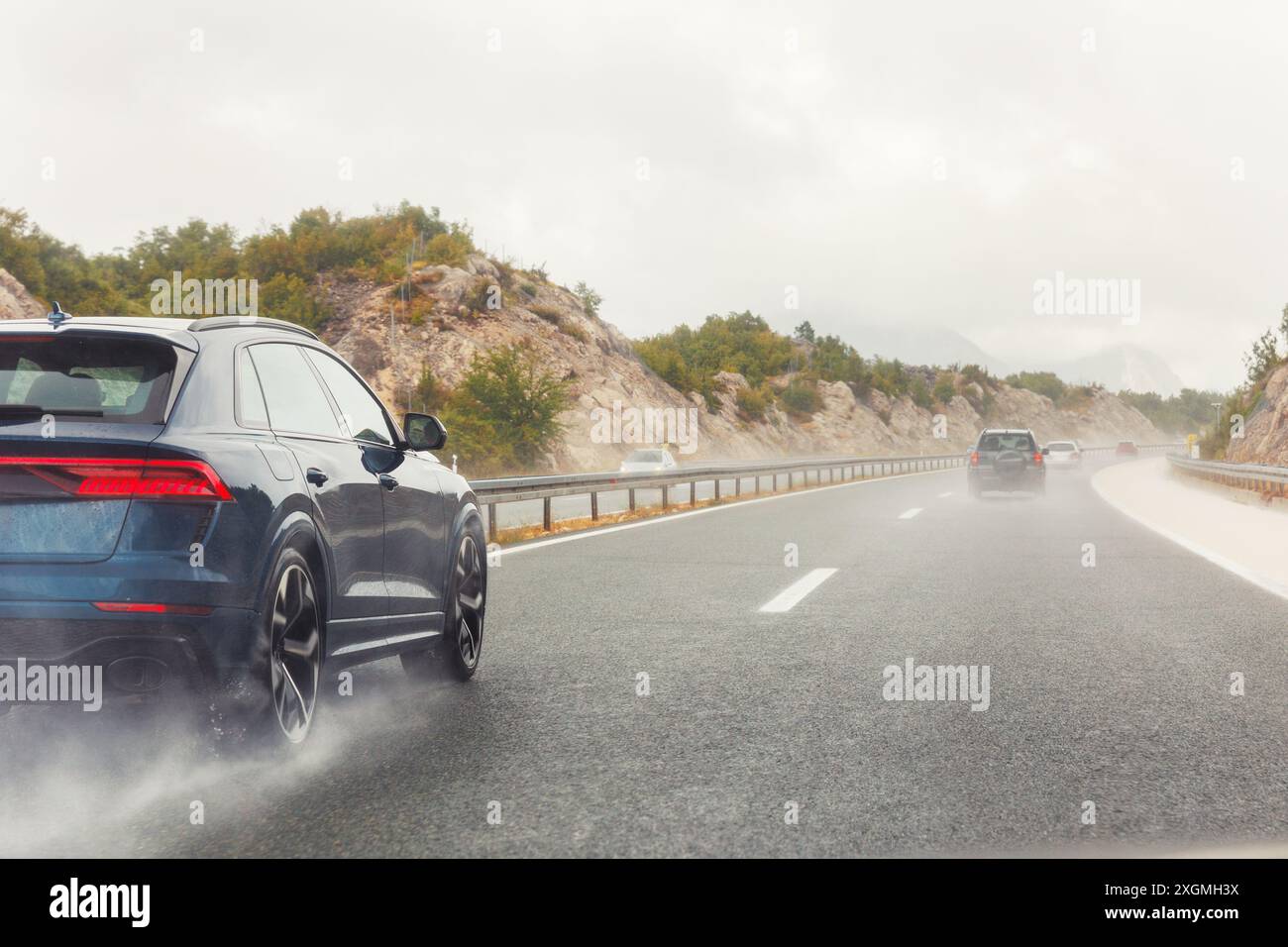 Back tail view of many cars driving fast on wet highway road after rain ...