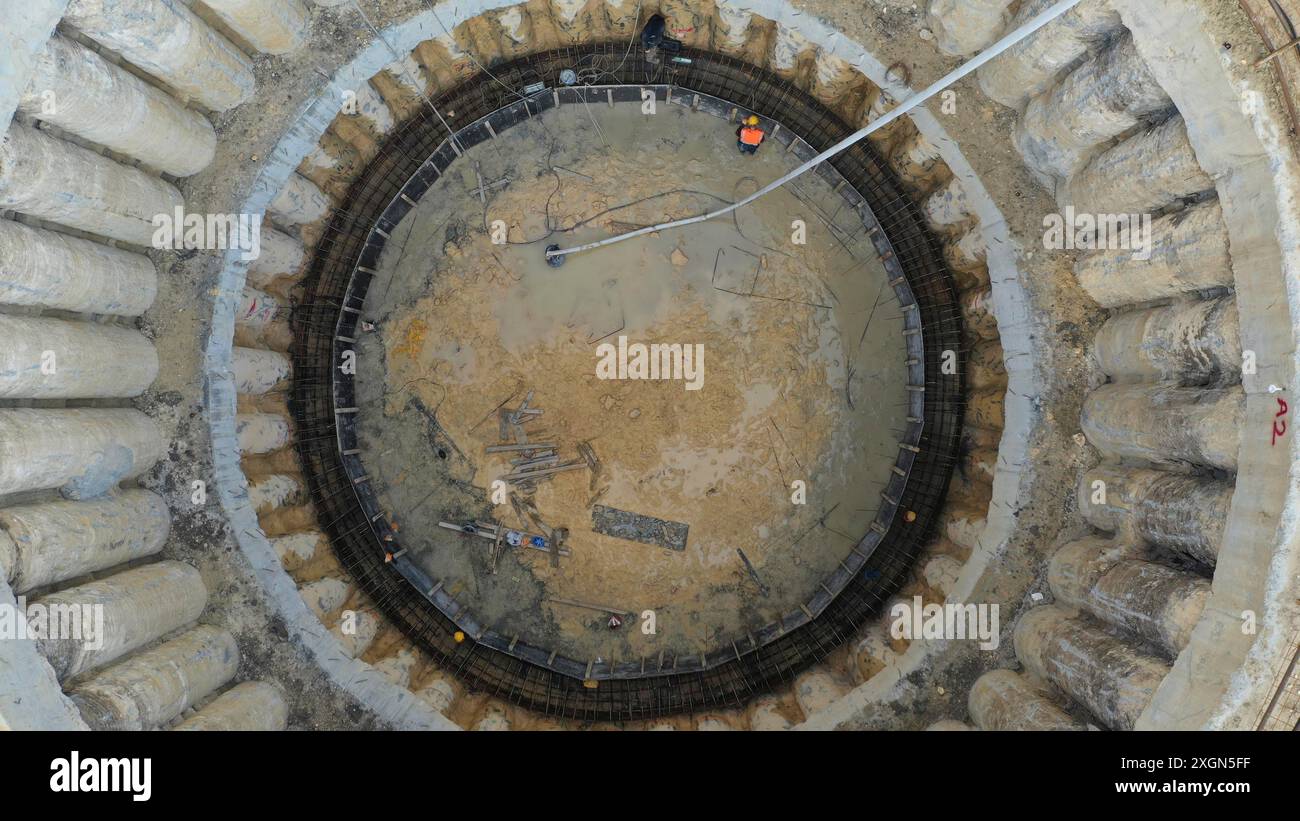 Top-down view of a circular construction pit with workers and ...
