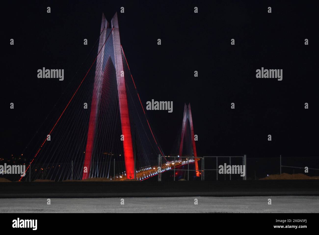 Illuminated bridge at night with red lights and a striking ...