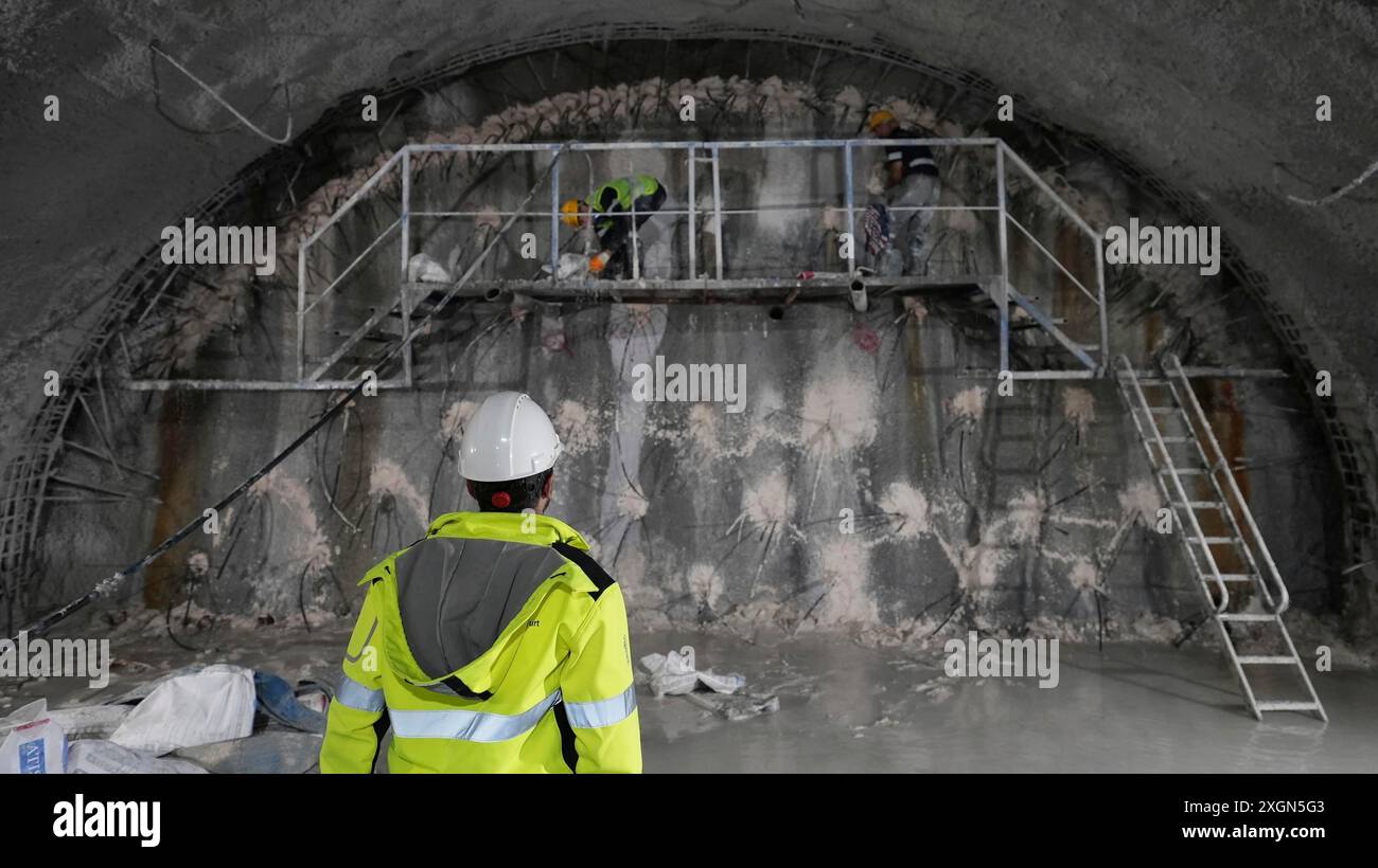 Inside view of a tunnel construction site with workers in safety gear ...