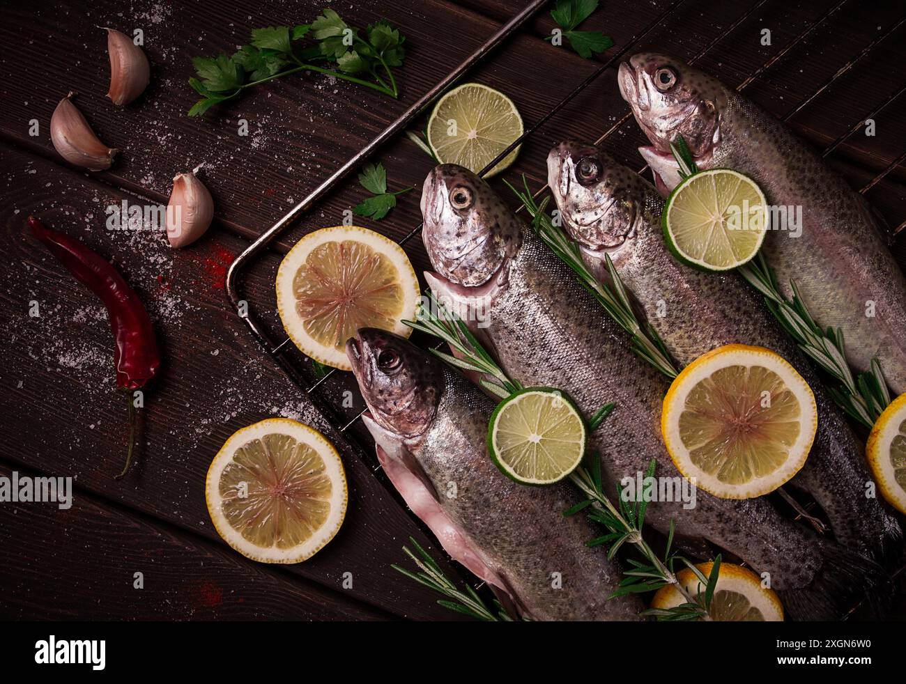 Raw rainbow trout, with lemon and herbs, on a wooden table, no people ...