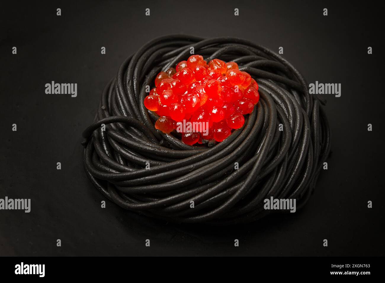 Black spaghetti with red caviar, pasta, on a black background, top view ...
