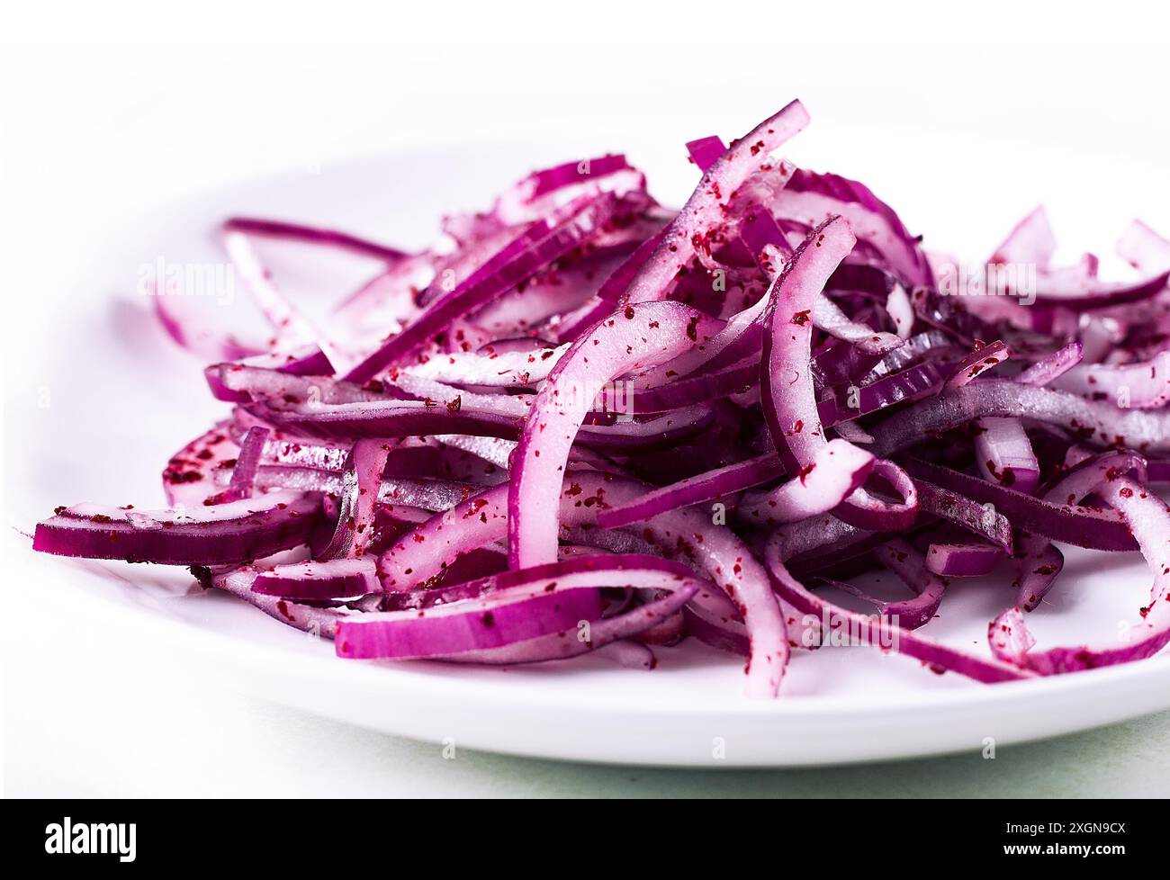 Sliced into half rings, red onion, with Sumac spice, on a white ...