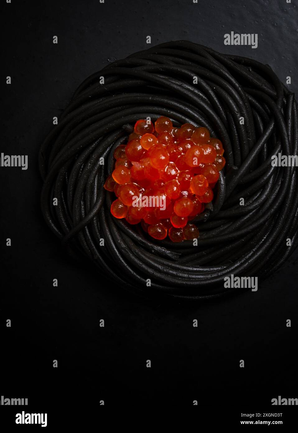 Black spaghetti with red caviar, pasta, on a black background, top view ...