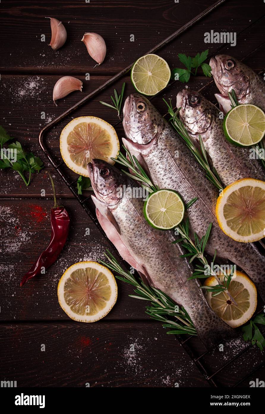 Raw rainbow trout, with lemon and herbs, on a wooden table, no people ...